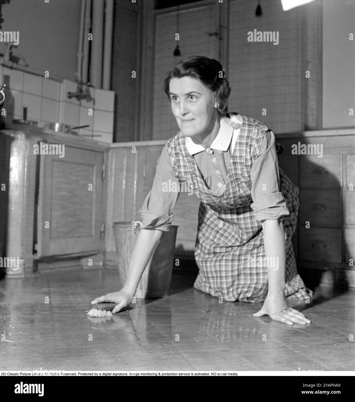 Scrubbing the floor in the 1940s. A woman is seen lying on her knees ...