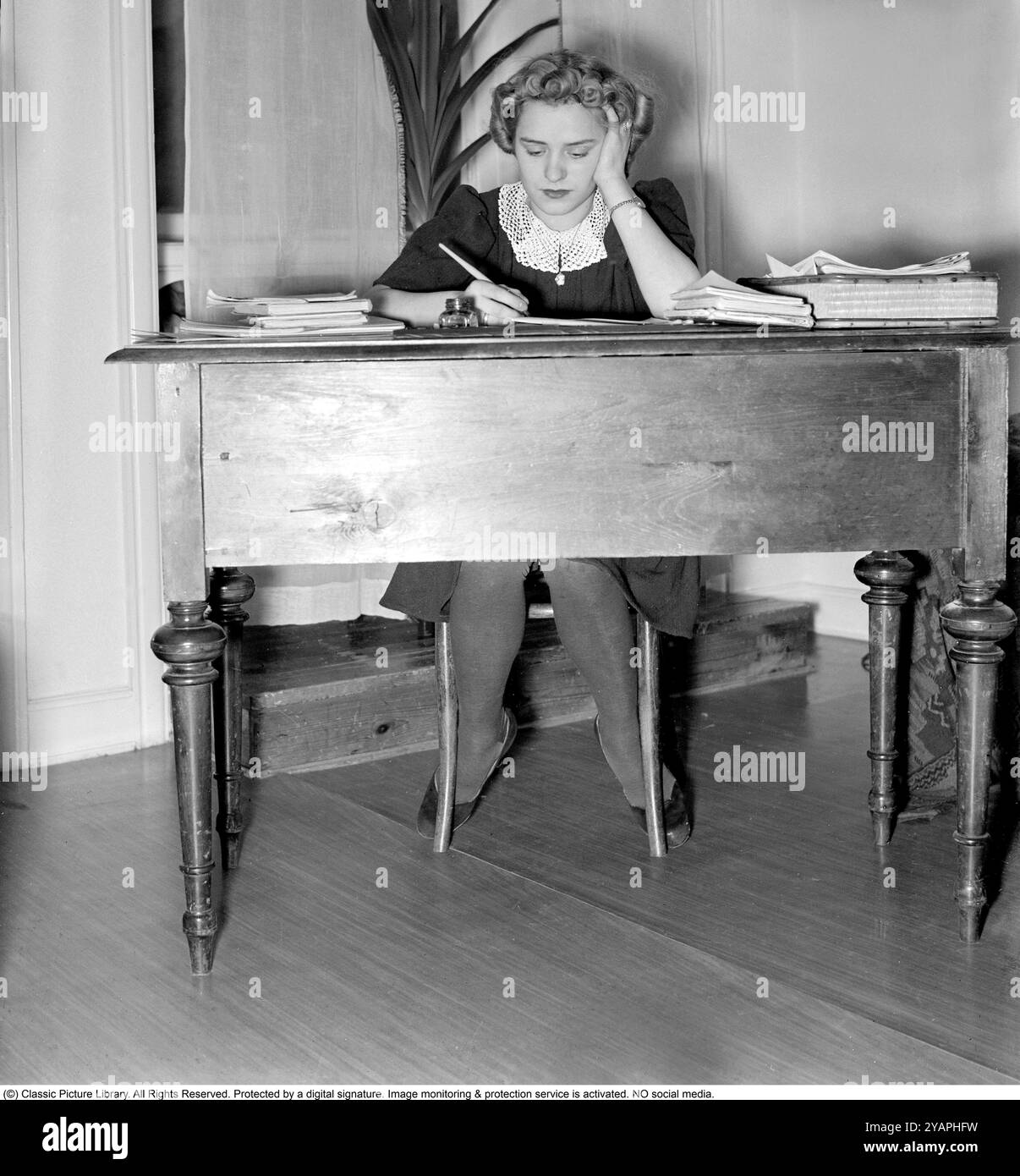 Studying in the 1940s. A young woman with his study books in front of ...
