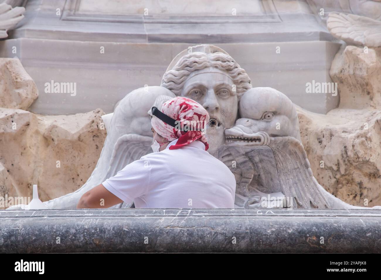 A restoration worker works on cleaning the marble statues from the ...
