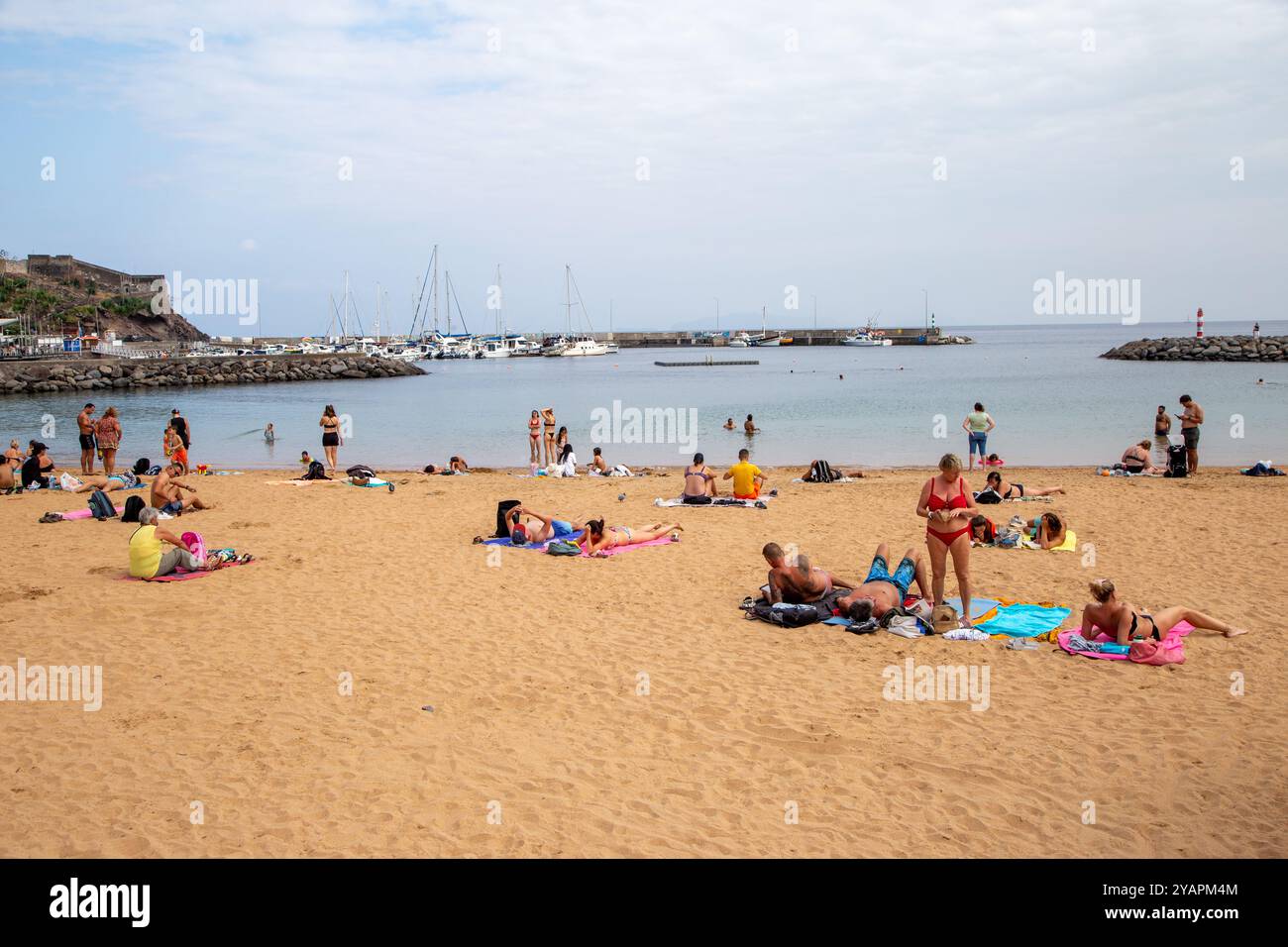 Holidaymakers and people sunbathing on vacation on the man made beach ...