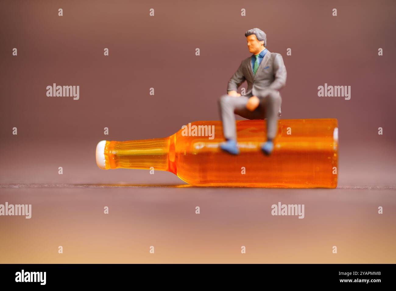 Conceptual image depicting alcoholism with a small businessman figure ...