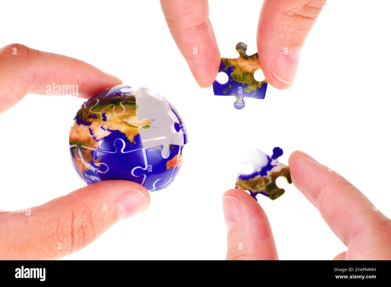 Three hands fitting pieces into a globe puzzle, illustrating the ...