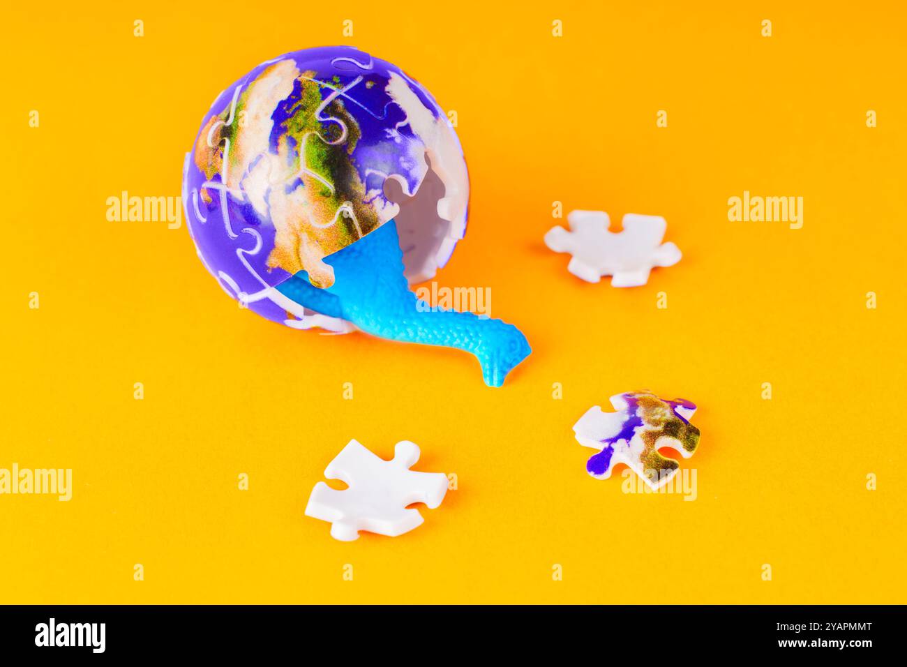 Blue dinosaur hatching from a puzzle globe with scattered puzzle pieces ...