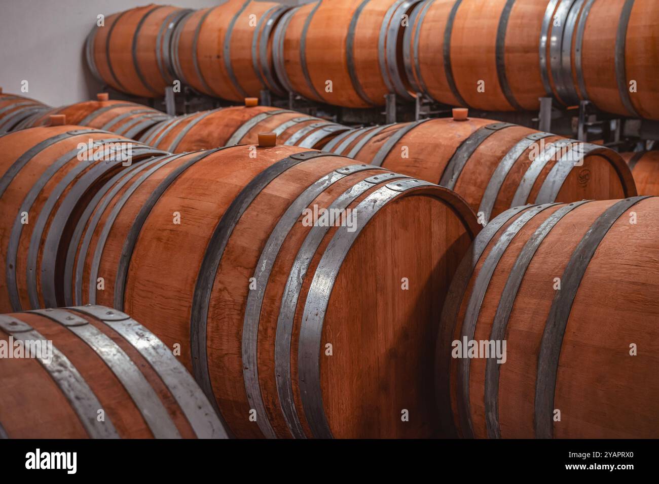 Wooden barrels stacked in wine cellar, showcasing the craft of aging ...