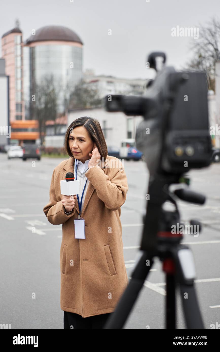 A female journalist readies her microphone to report in a busy city ...