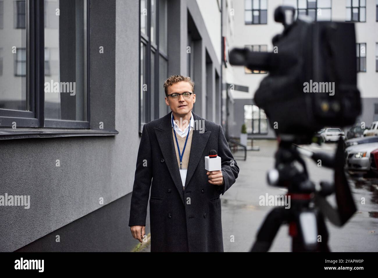 A dedicated news anchor interviews outside, holding a microphone while ...