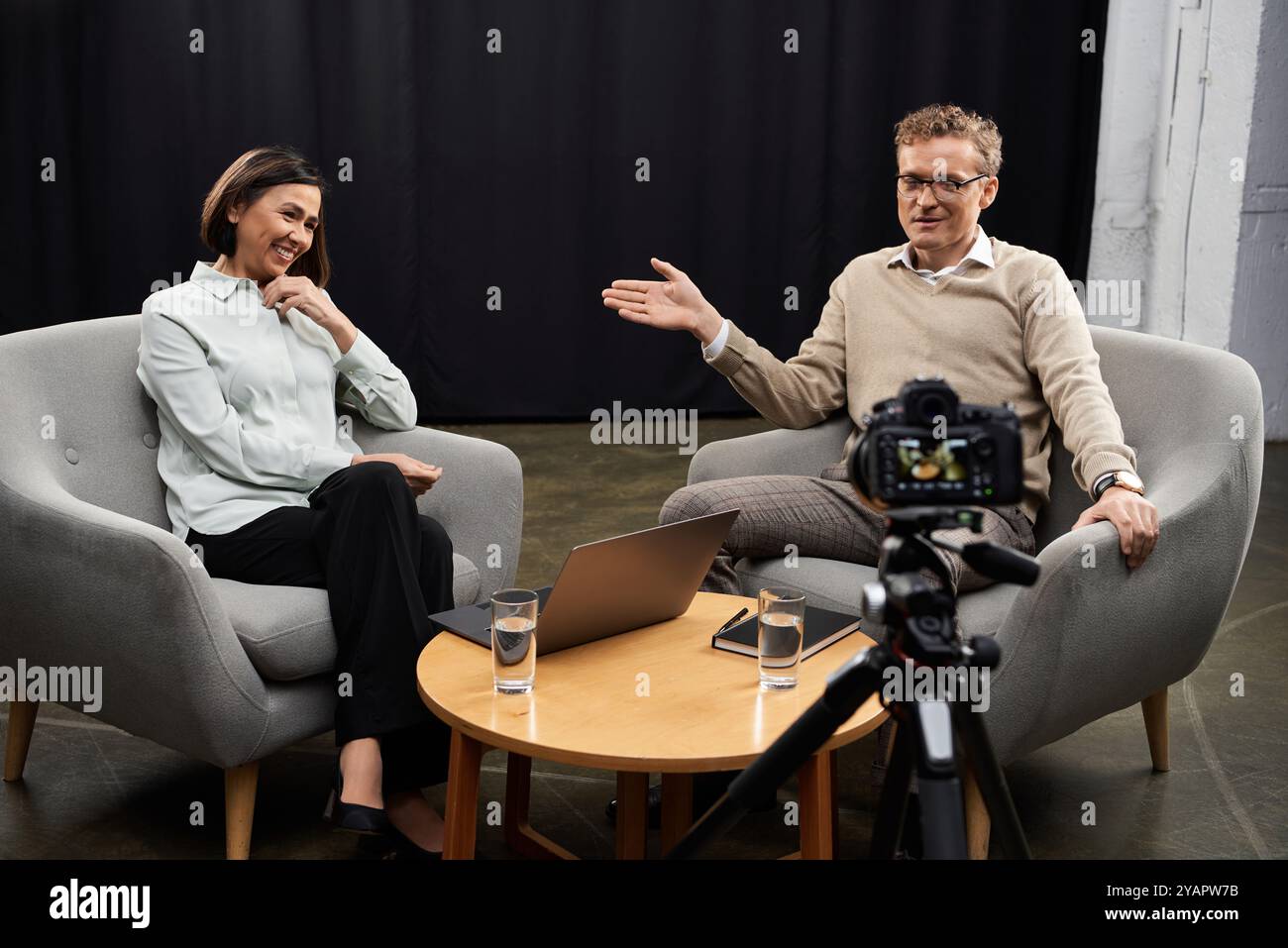 A middle aged female journalist engages with a male expert in a ...