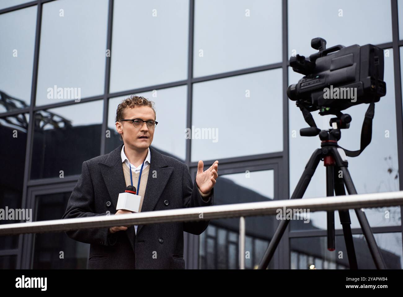 A news anchor wearing glasses passionately speaks into a microphone ...