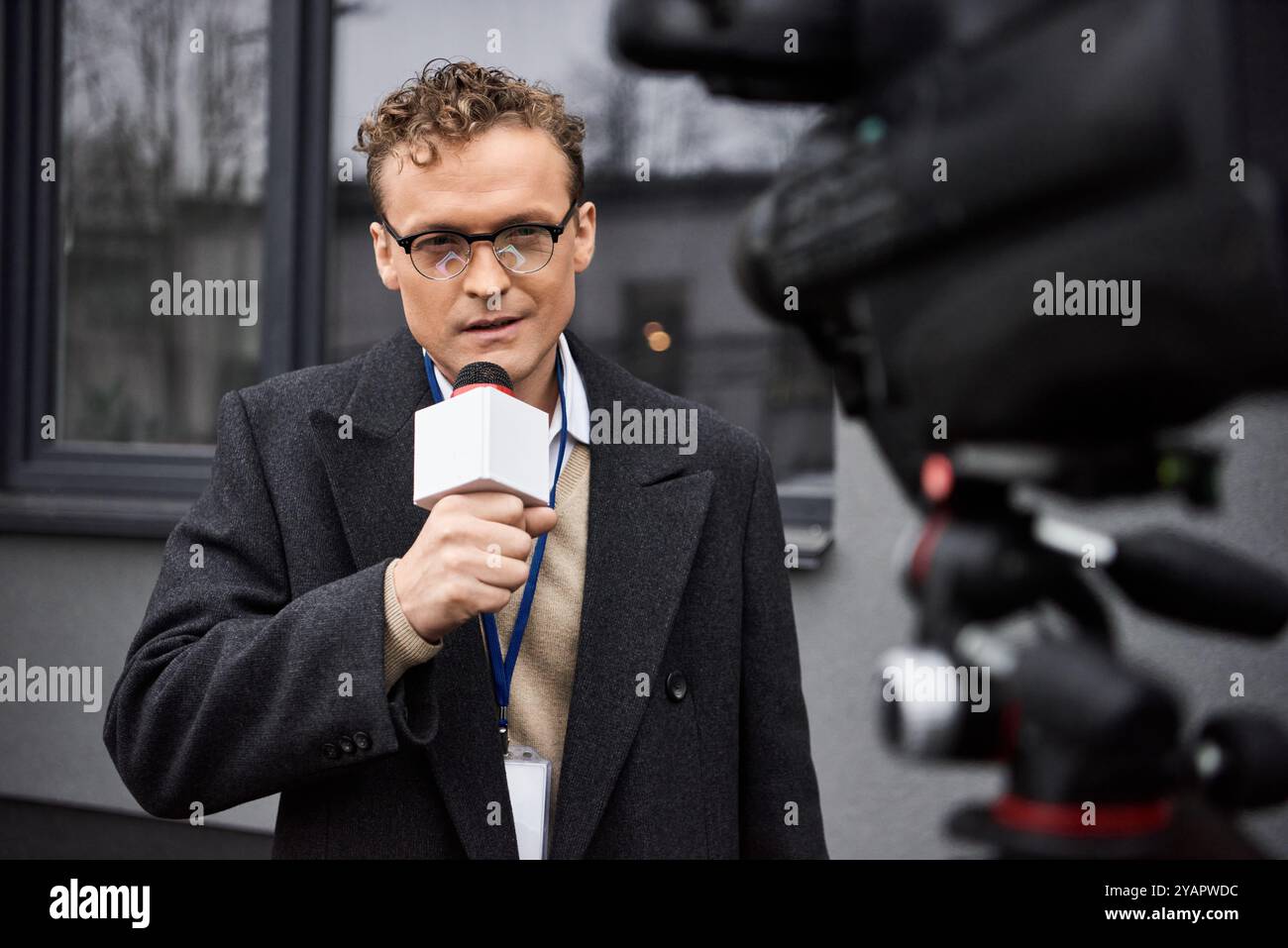 A professional journalist speaks into a microphone, reporting live from ...