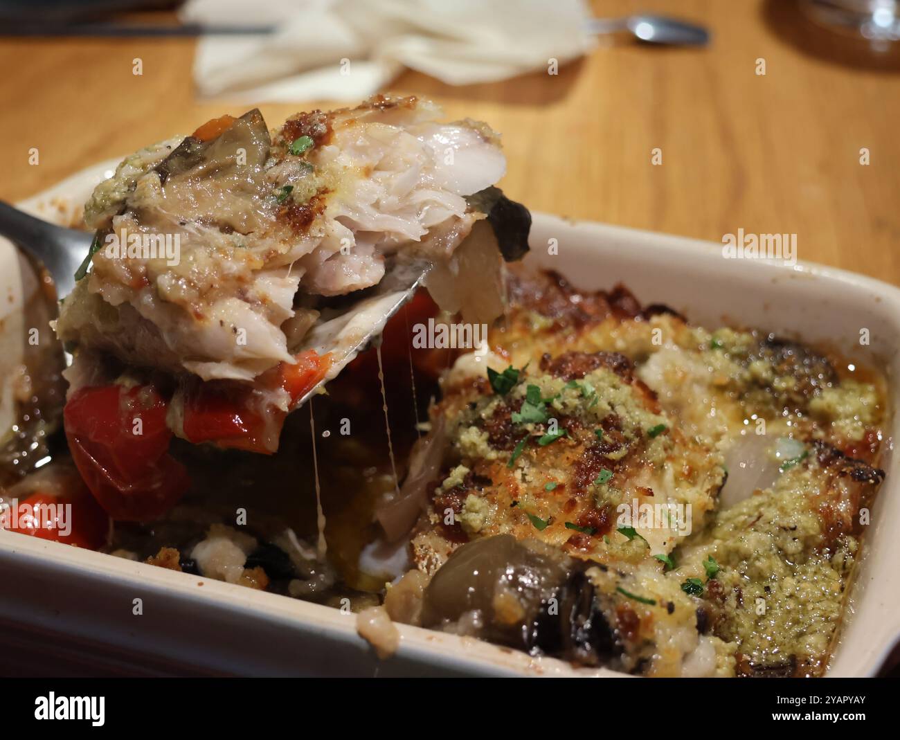 A plate of food with a spoon in it. The spoon is in the middle of the ...