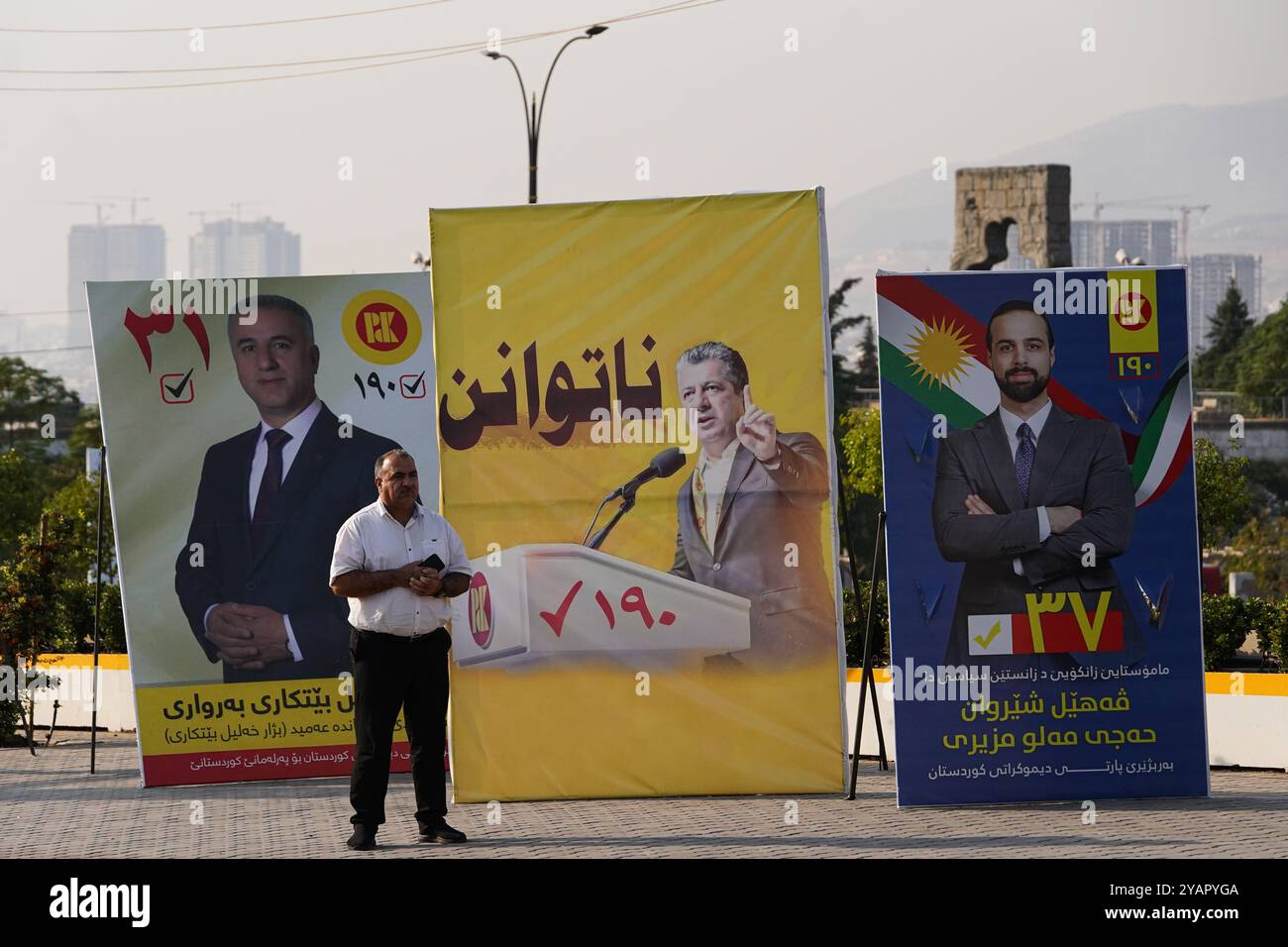 A man stands alongside the road past electoral banners of the Kurdistan ...