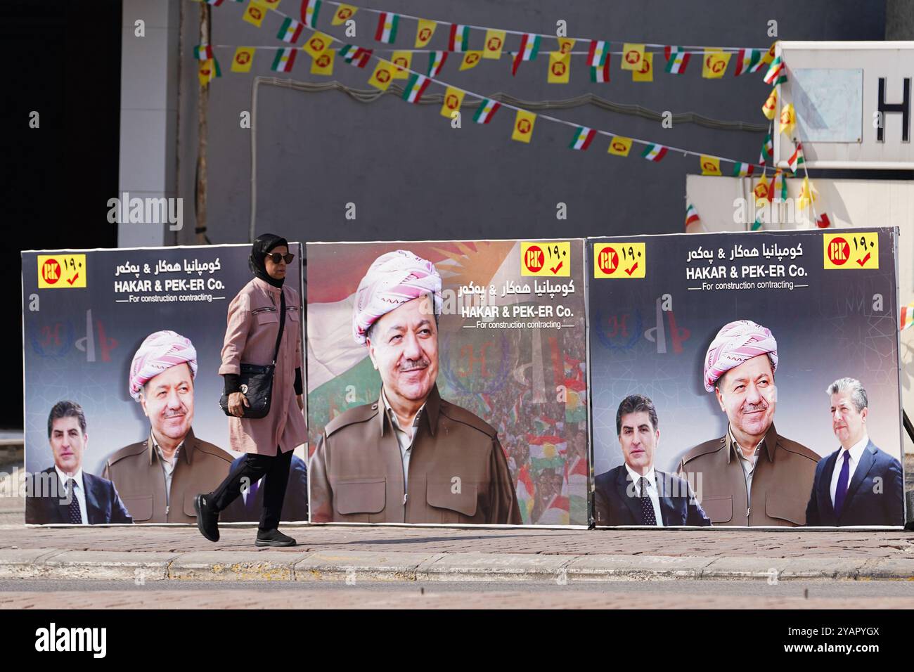 A woman walks past banners of the Kurdistan Democratic Party (KDP/PDK ...