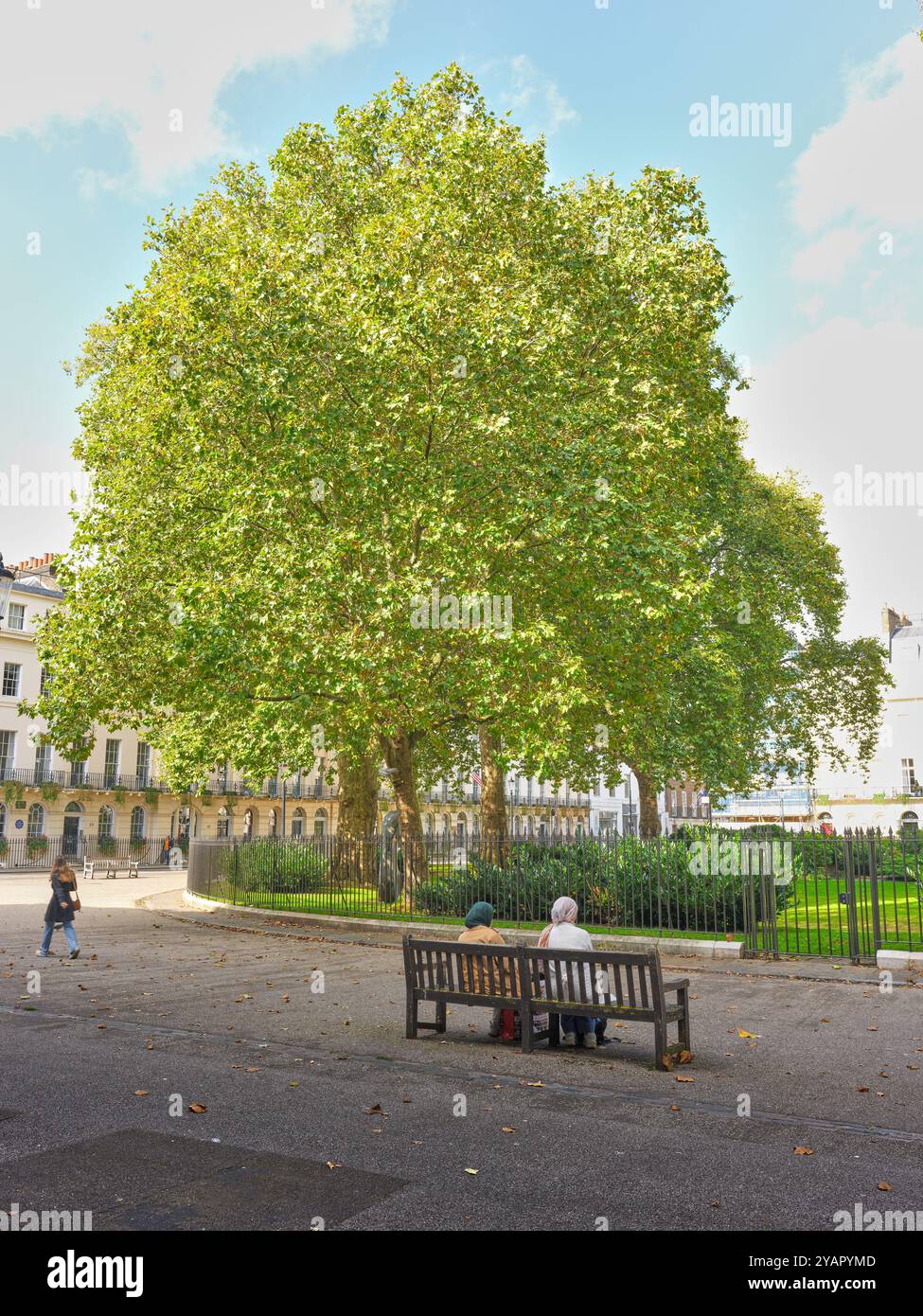 A couple sit on a bench outside the garden at Fitzroy Square, London ...