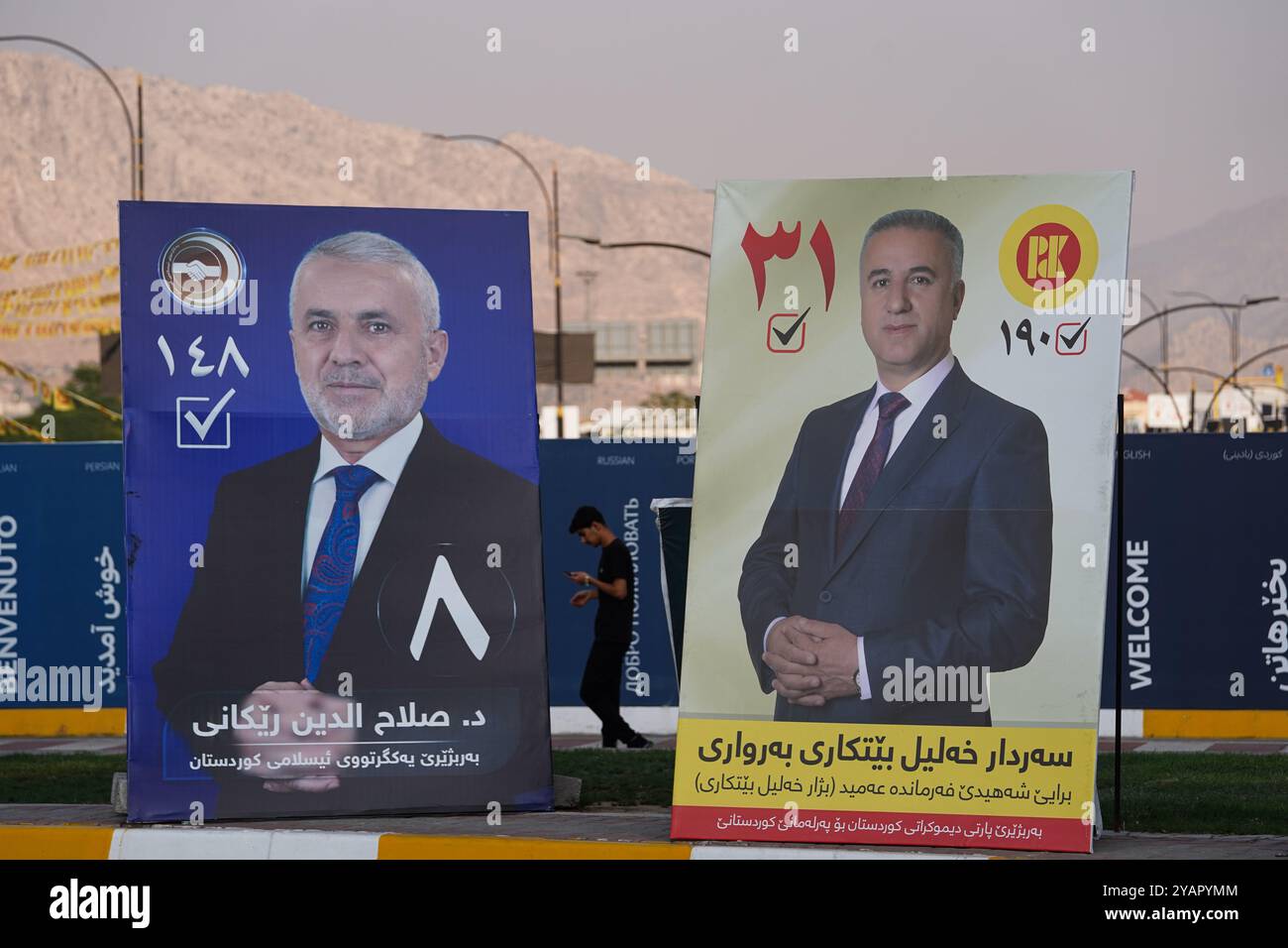 A young man walks along the side of the road past electoral banners of ...