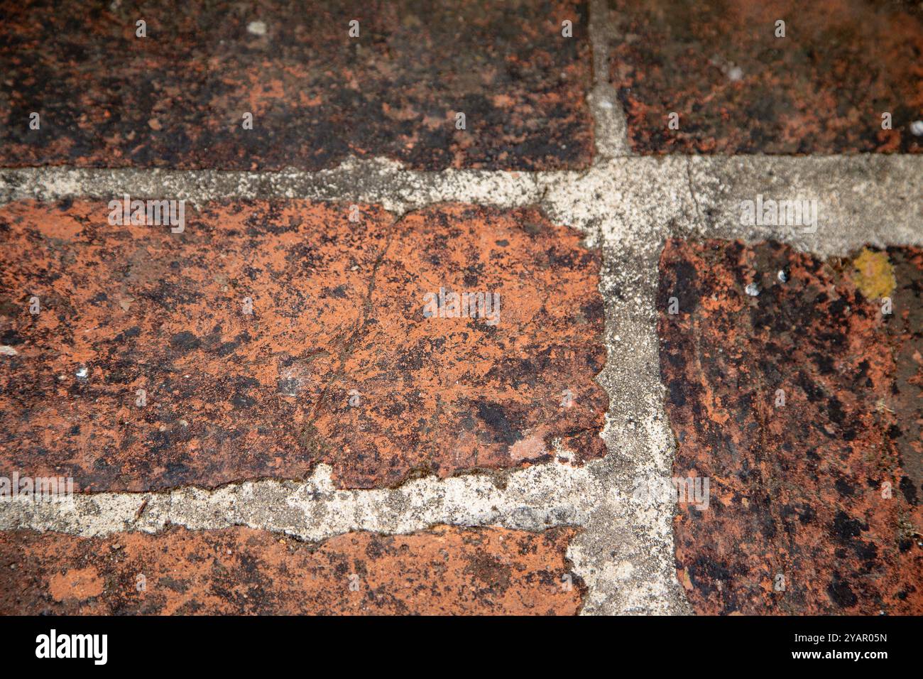 A close-up view of an aged and worn brick textured surface with mortar ...