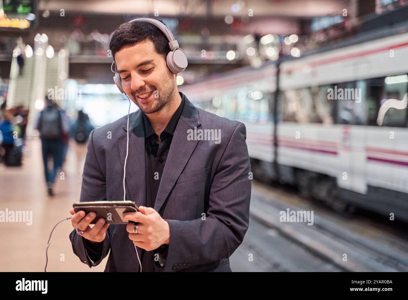 man waiting in an underground station using his smart phone watching ...