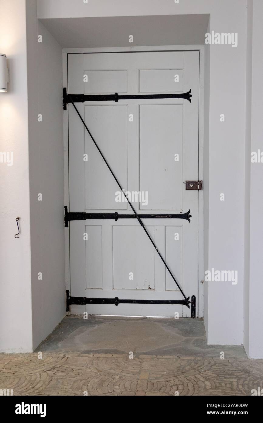 A rustic white wooden door with black iron hinges and a diagonal ...