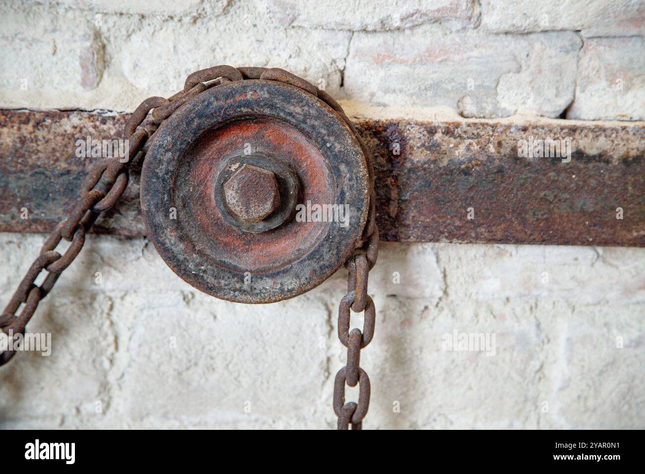 Rusted metal pulley system with chains mounted on a weathered brick ...