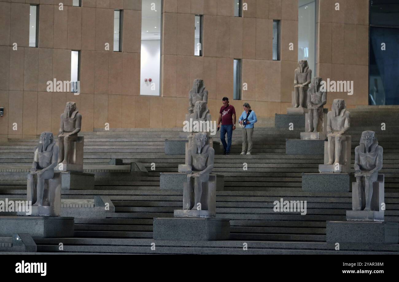 Visitors walk past ancient Egyptian statues along the Grand Staircase ...