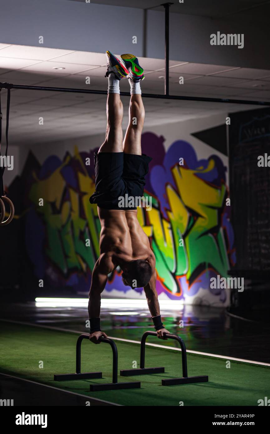 A fit male athlete executes a precise handstand on gymnastic parallel ...