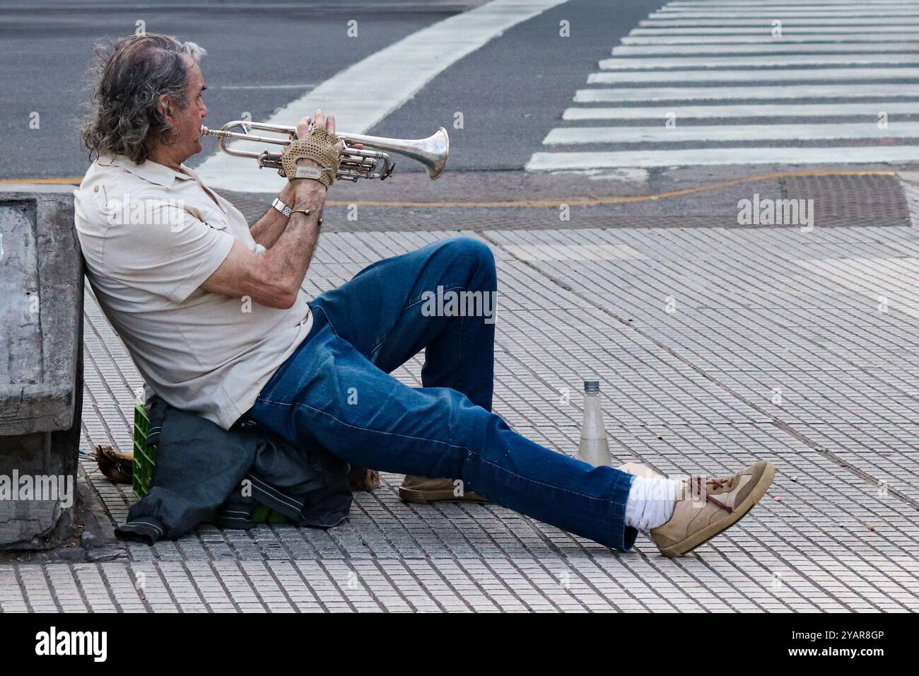 homeless man sitting in a corner playing a trumpet and wearing blue ...