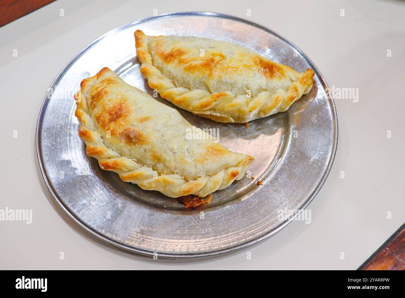 Two meat pies on a stainless steel plate from a pizzeria and fast food ...
