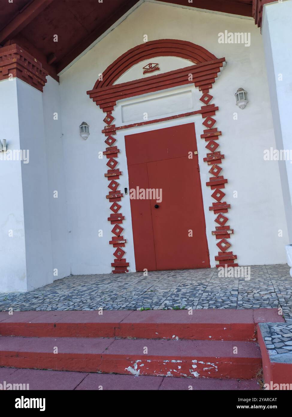 small white building with red accents and a mosaic-tiled entrance ...