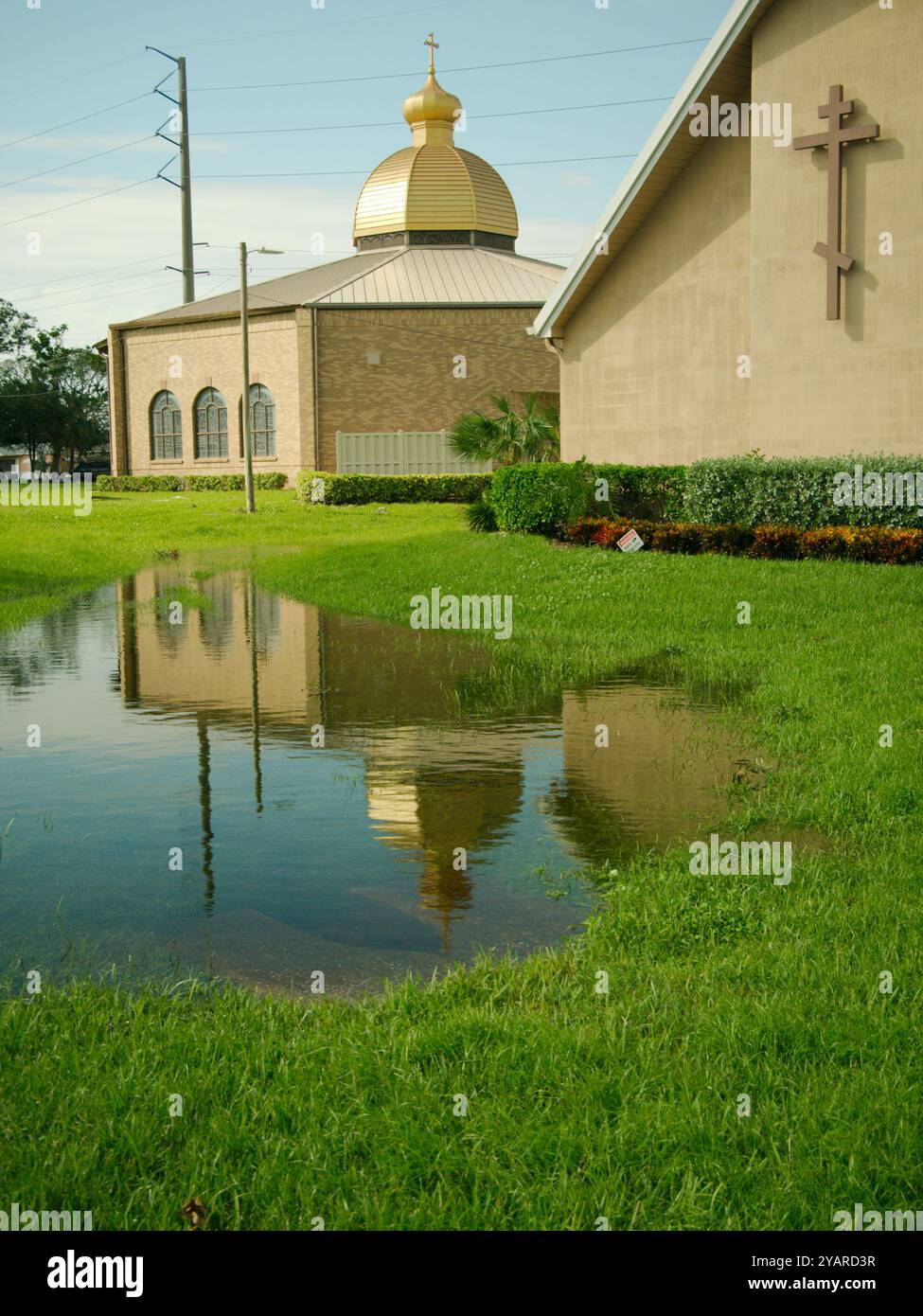 Tall view church building with cross reflecting in a pool of water with ...