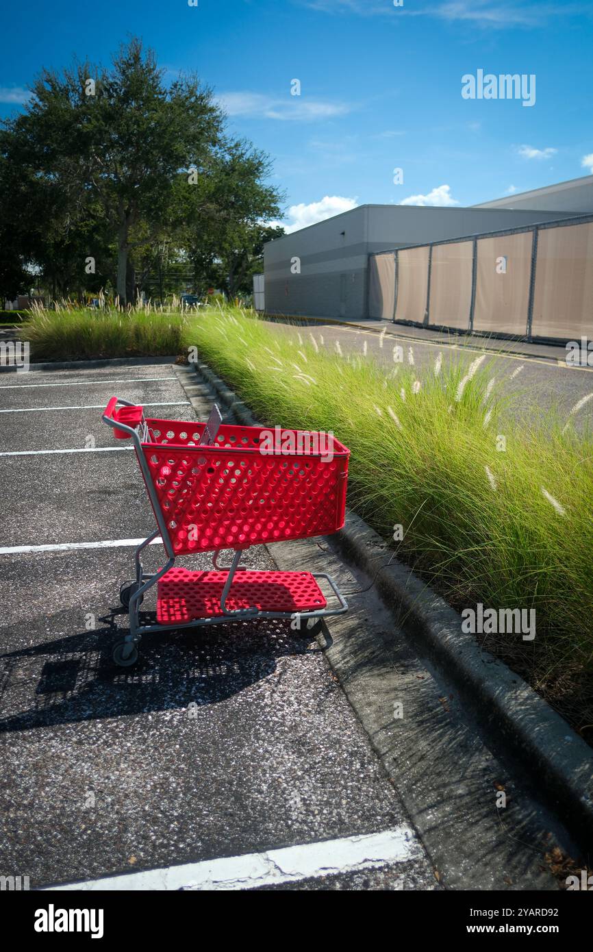 An isolated red shopping cart trolley in the car park of a retail store ...