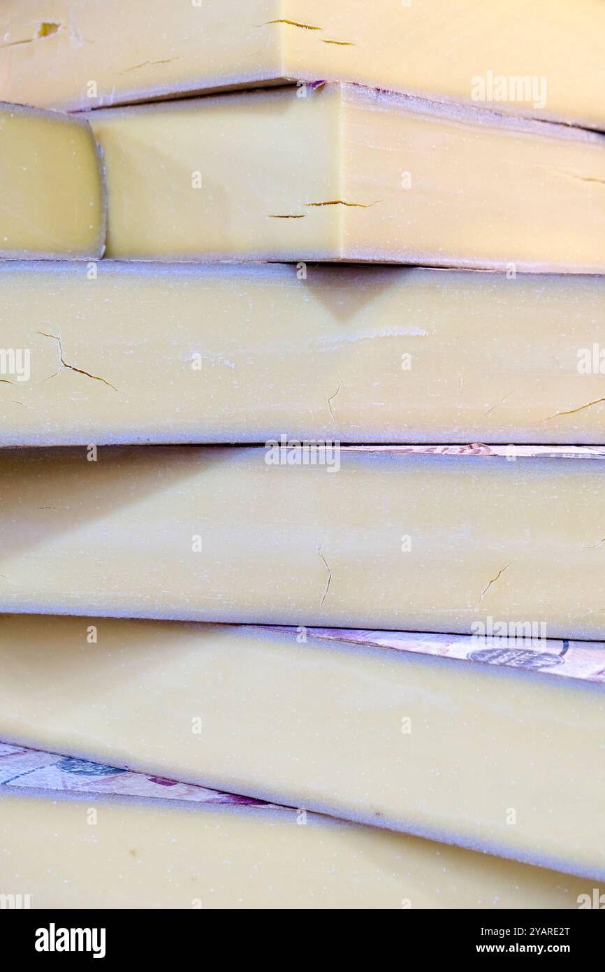 A stack of cut wheels of French Comte cheese on display at the front of ...