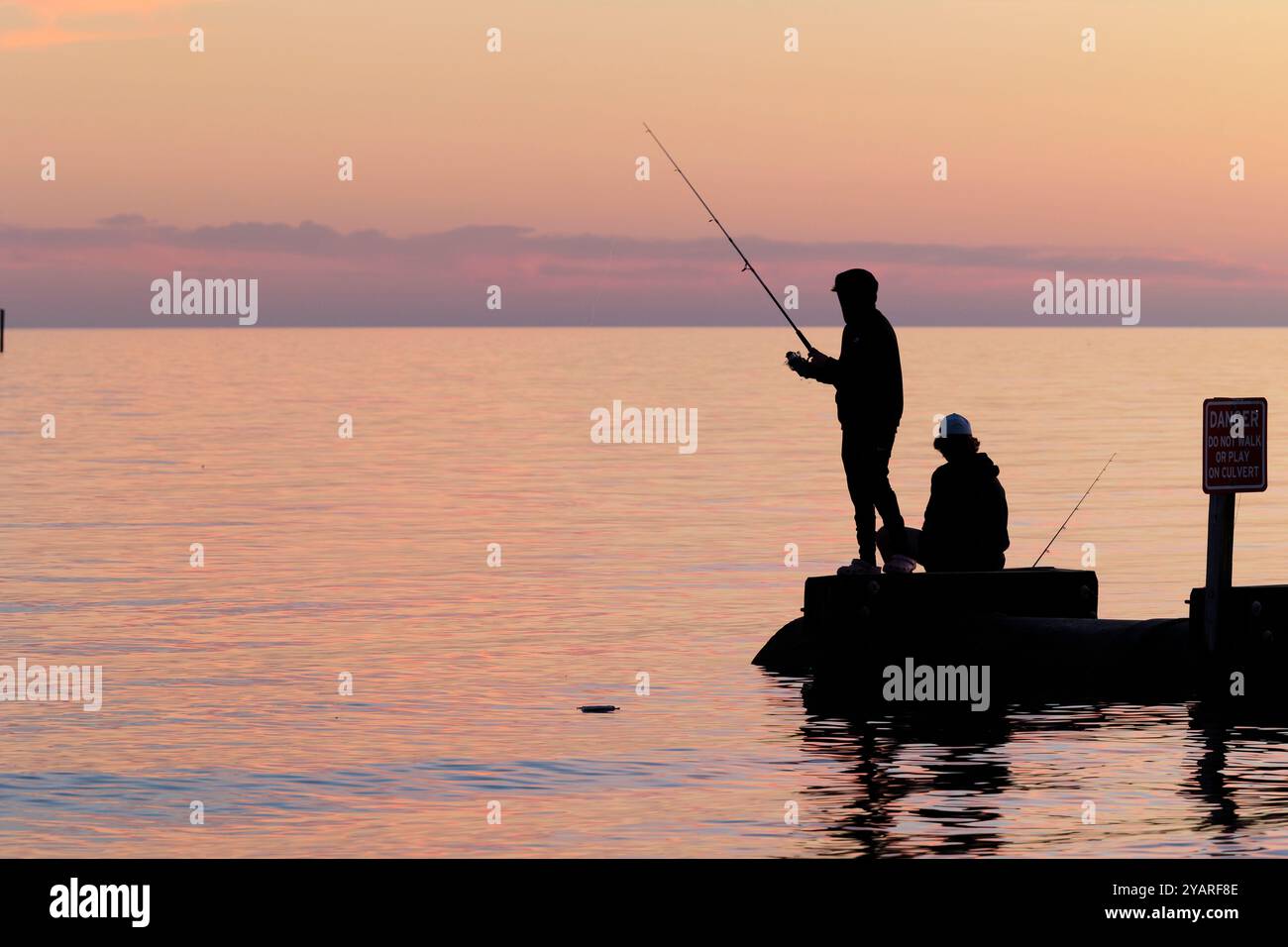 Silhouette of young adults ignoring danger sign while fishing on storm ...