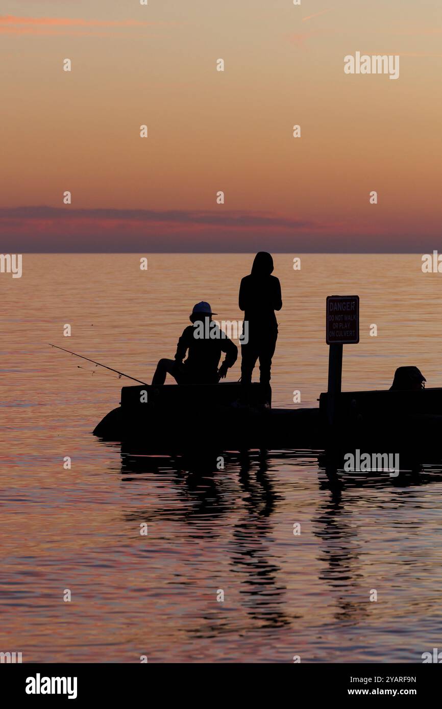 Silhouette of young adults ignoring danger sign while fishing on storm ...