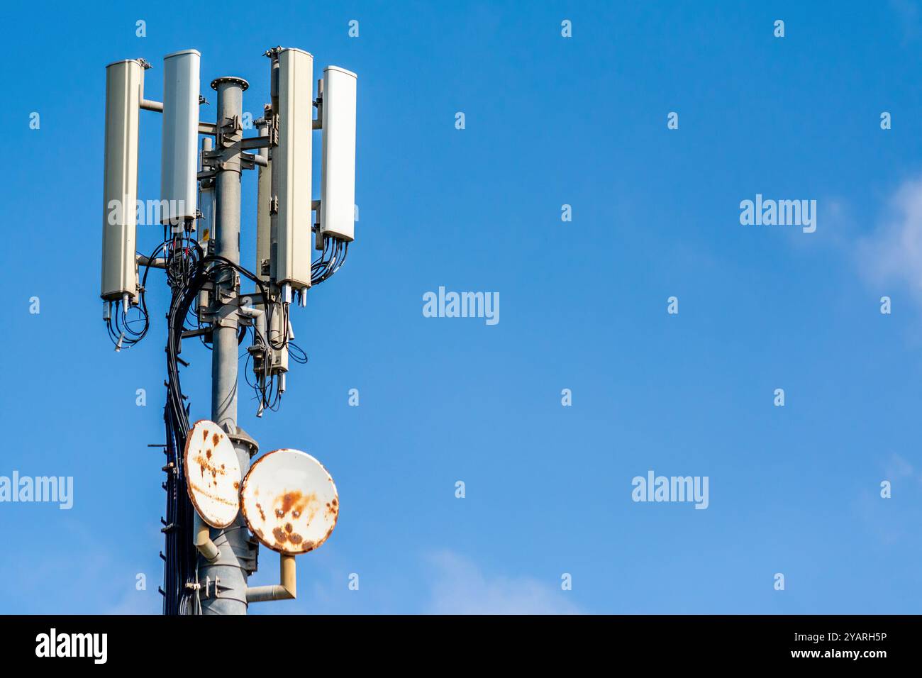 Antennas on a metal pole under a blue sky with clouds Stock Photo - Alamy