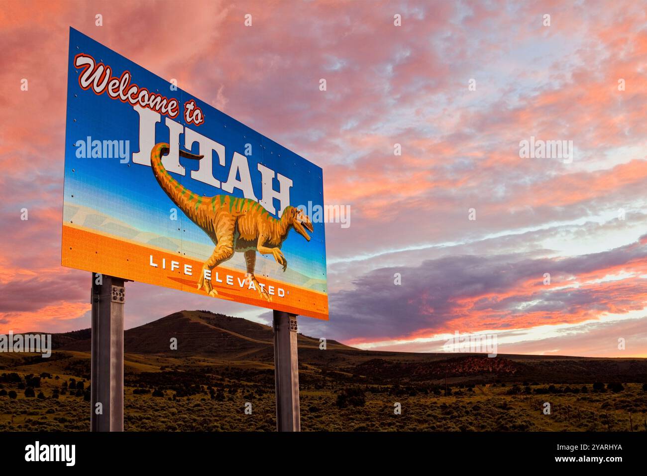 A "Welcome to Utah" sign featuring a dinosaur stands along a rural Utah ...