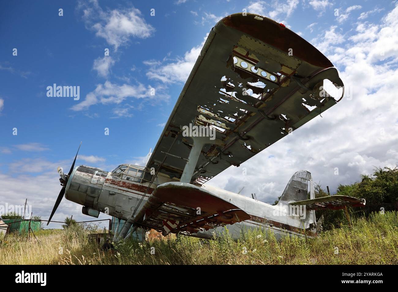 Old crashed and abandoned plane standing in the field against cloudy ...