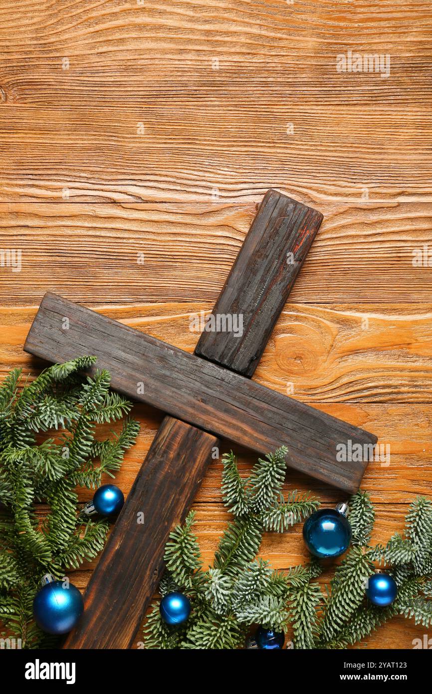 Cross with fir branches and balls on wooden background. Christmas story ...