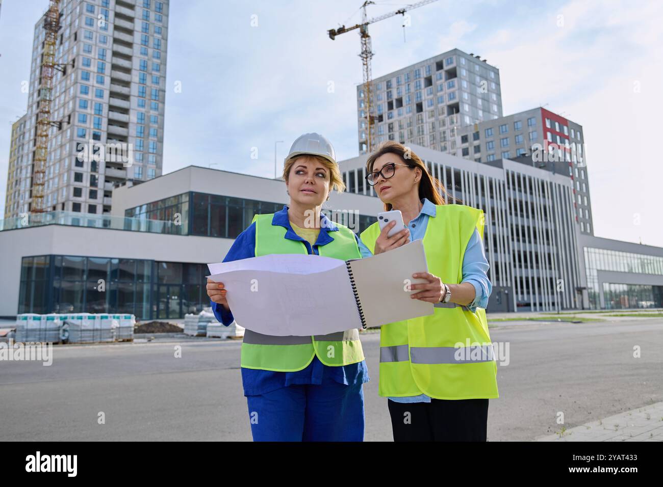 Two confident women talking working on construction of residential ...
