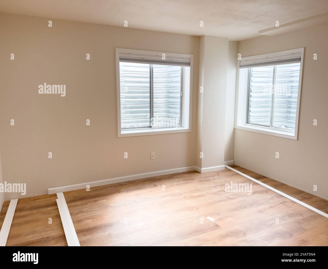 Installing White Vinyl Baseboards in a Newly Renovated Room with Wooden ...