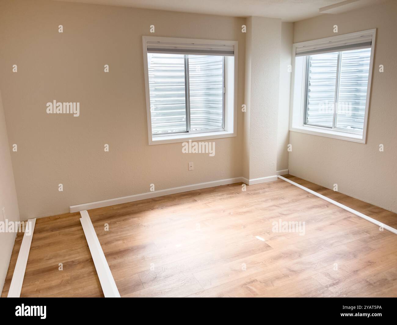 Installing White Vinyl Baseboards in a Newly Renovated Room with Wooden ...