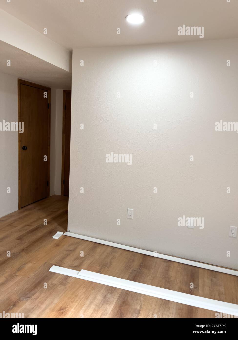 Installing White Vinyl Baseboards in a Newly Renovated Room with Wooden ...