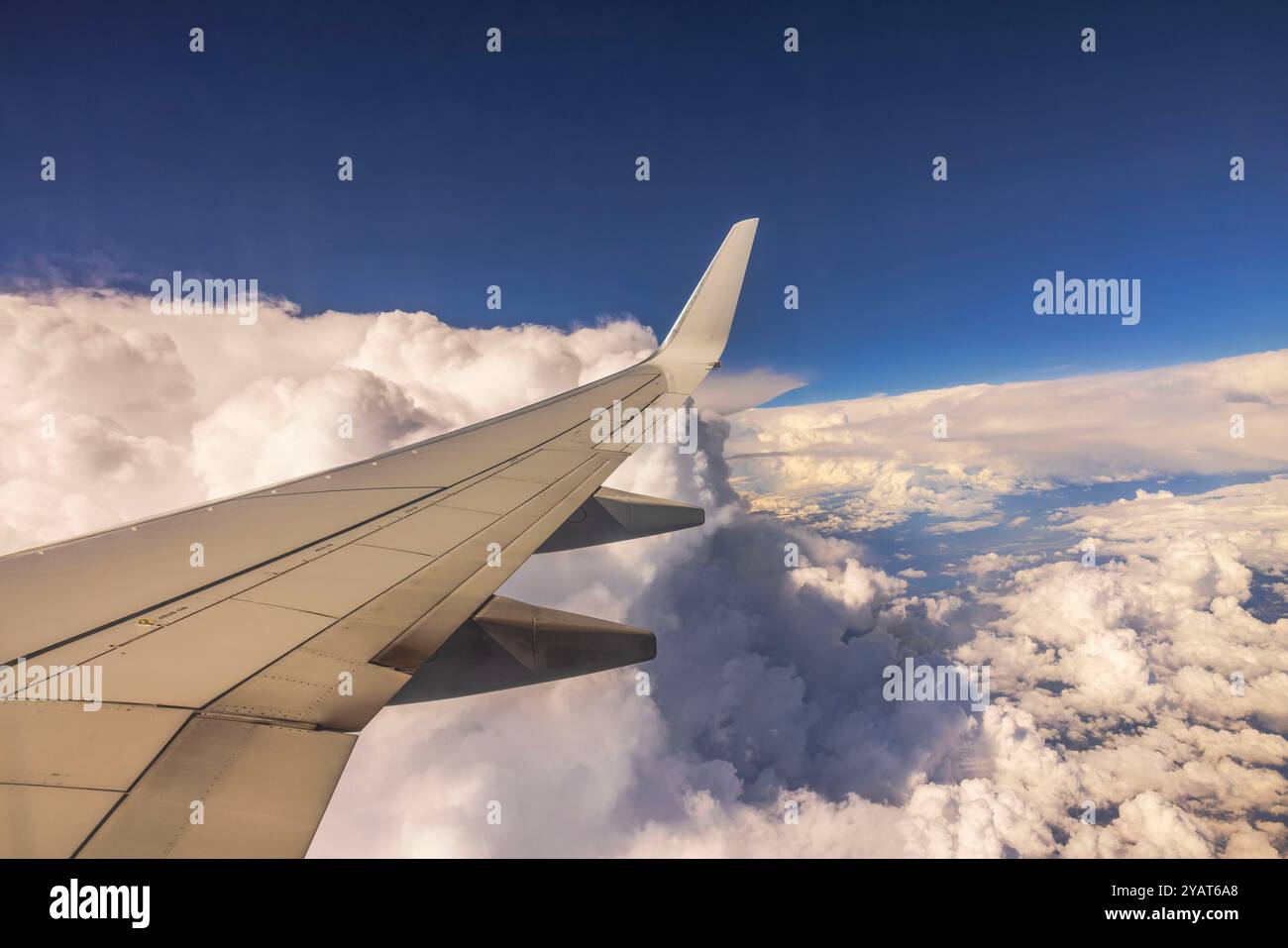 Airplane wing view during flight above clouds in bright blue sky with clouds Stock Photo - Alamy