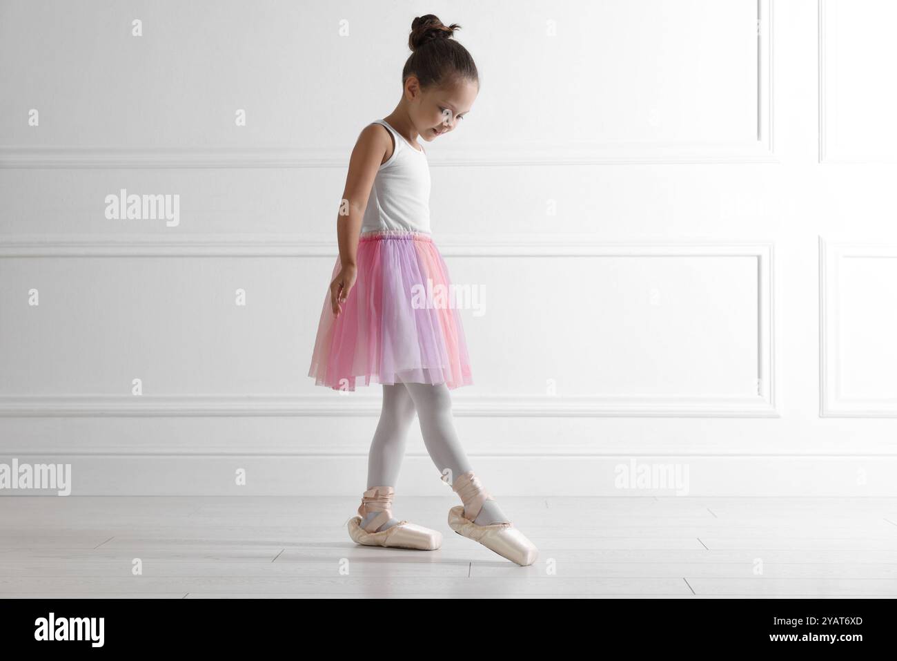Little ballerina practicing dance moves near white wall indoors Stock ...