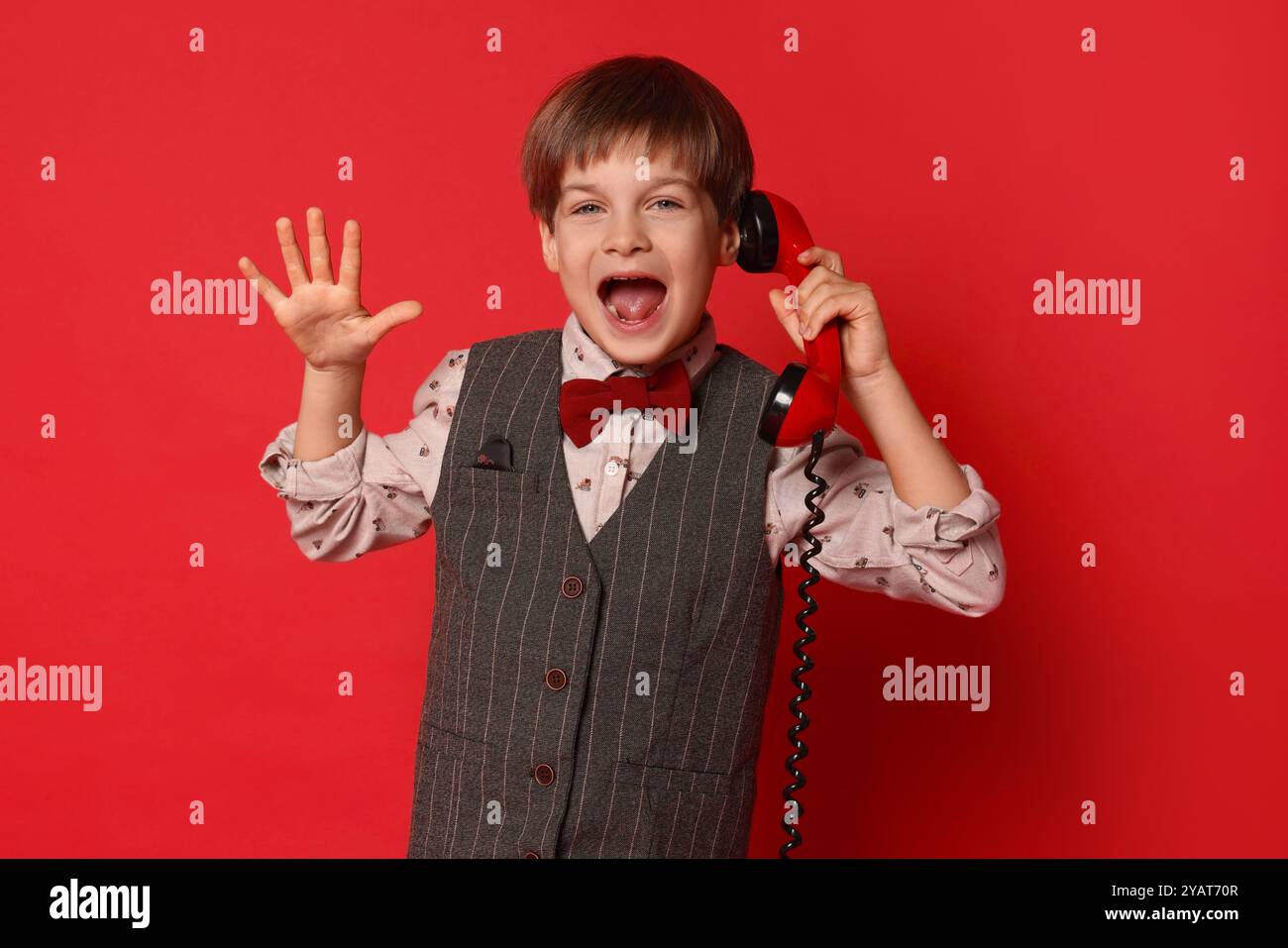 Cute little boy with handset of telephone on red background Stock Photo ...