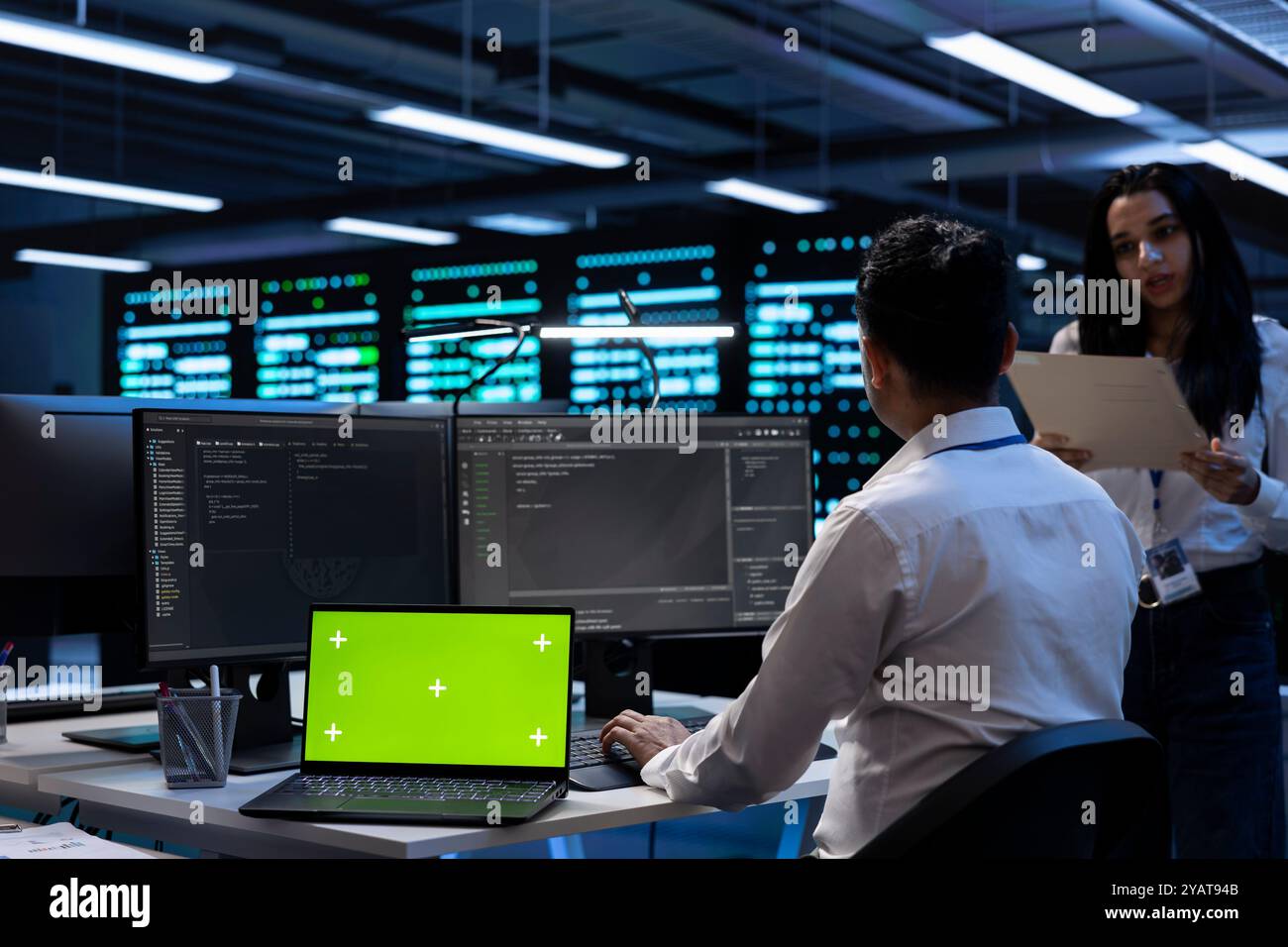 Teamworking technicians in server room using green screen laptop to find network issues ...