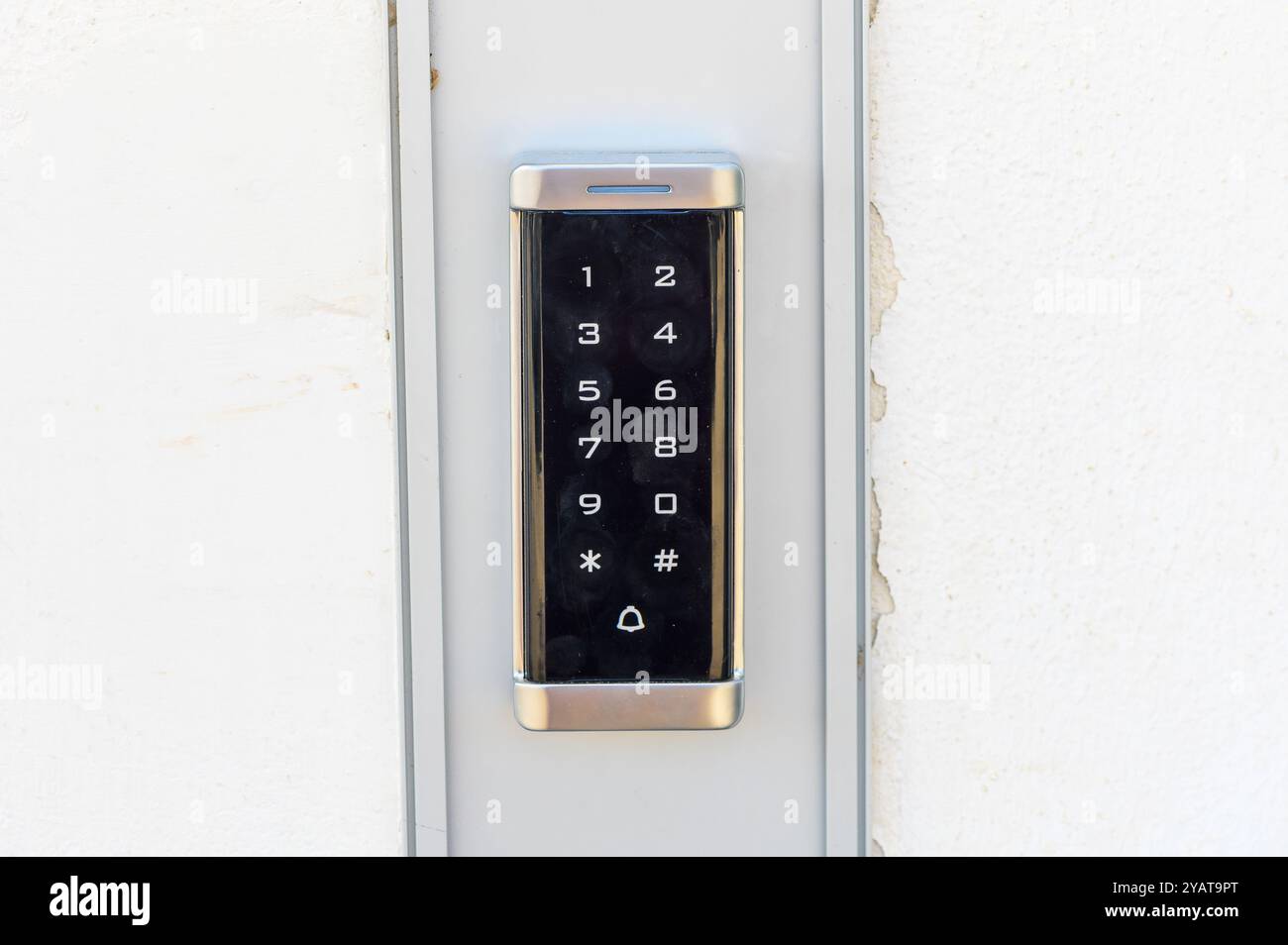 A sleek electronic keypad mounted on a white wall provides secure entry ...