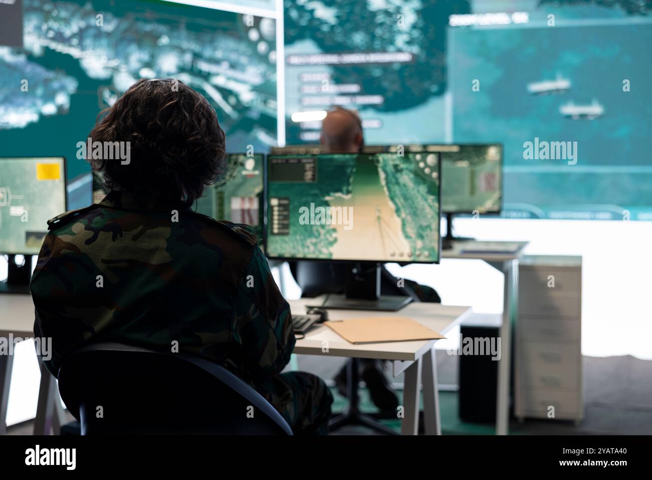 IT operator monitoring surveillance radar footage from CCTV system, using a big screen in ...