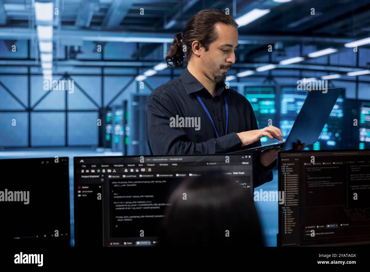 Engineer Standing In Data Center Typing On Laptop Doing Yearly Checkup To Avoid Equipment 