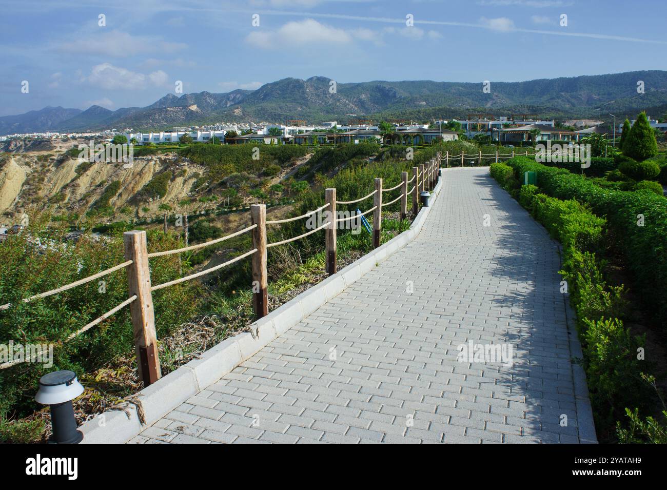 The winding pathway meanders along the cliff, surrounded by lush ...