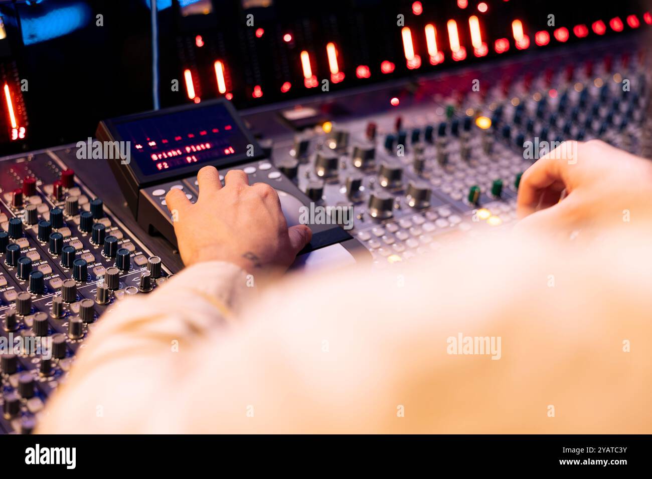 Tracking engineer pressing faders and buttons on control desk to ...