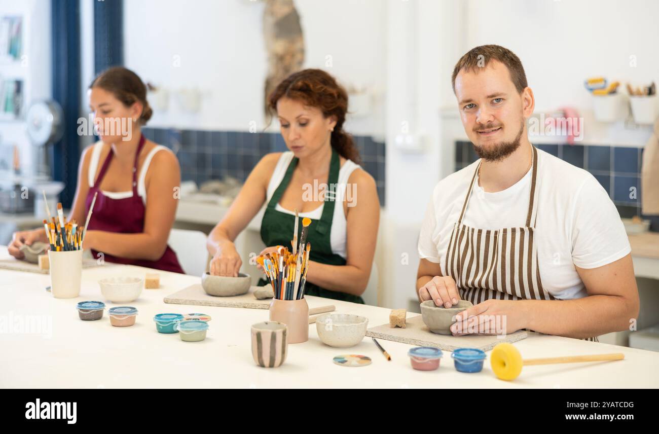 Three students in pottery workshop learn to create homemade plates and ...